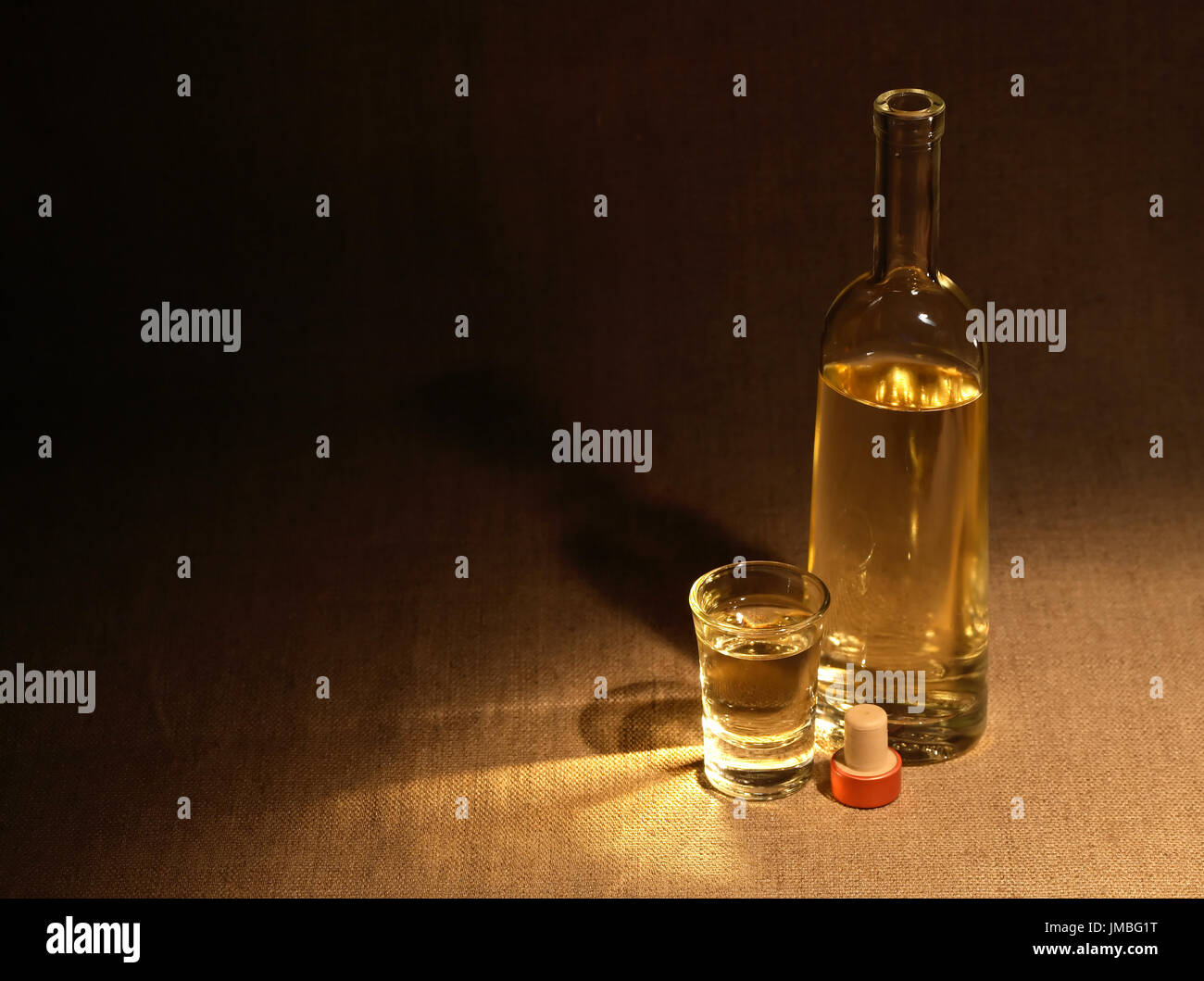 Open bottle of wine or vodka near wineglass on canvas surface under ...