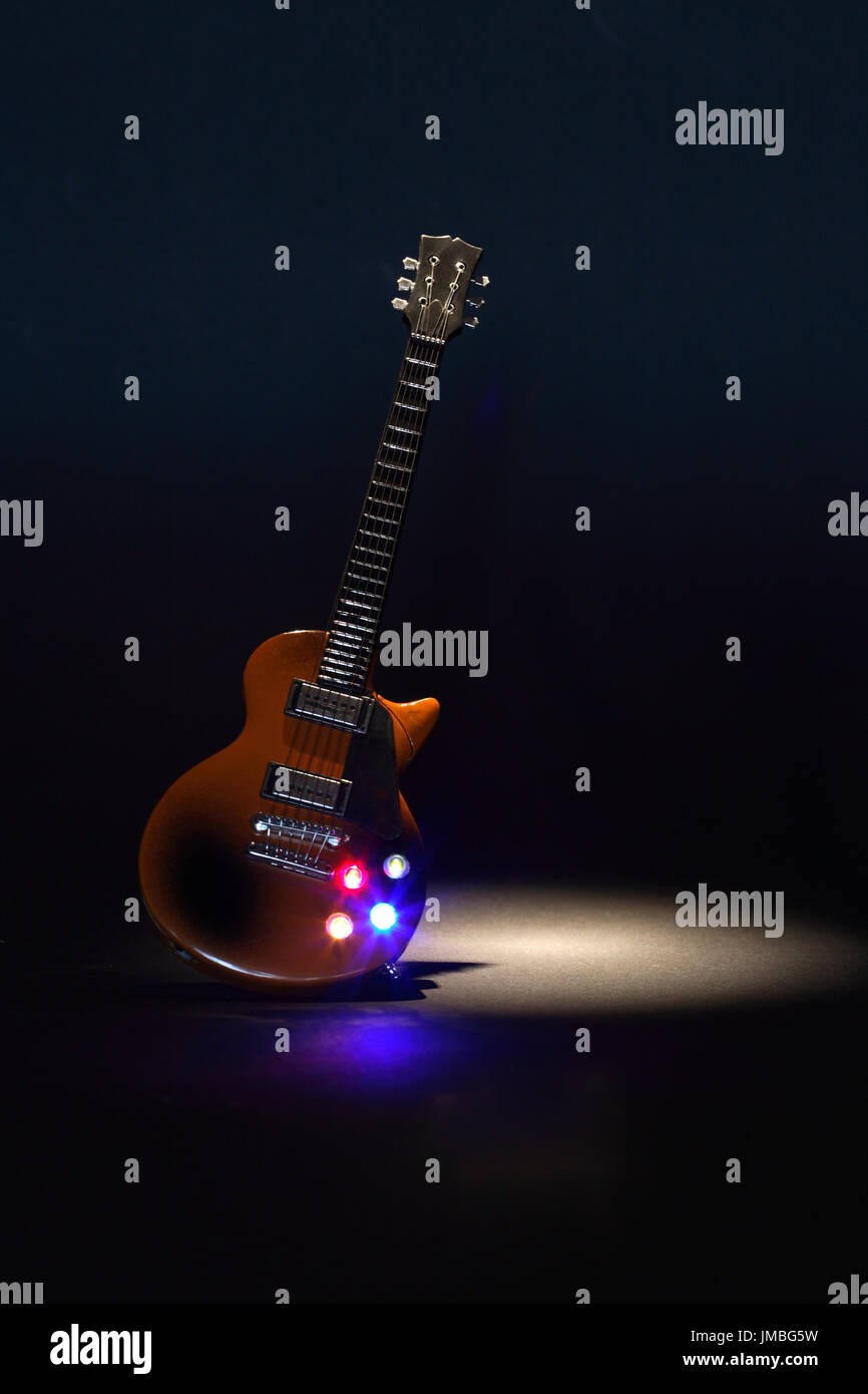 Electric guitar under beam of light on dark background Stock Photo - Alamy
