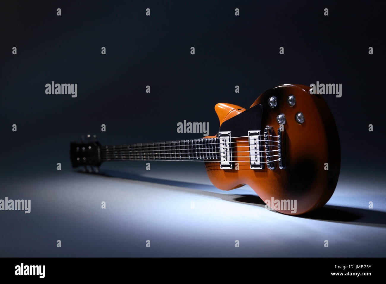 Electric guitar under beam of light on dark background Stock Photo - Alamy