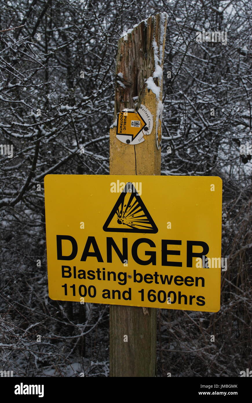 Yellow danger blasting sign by snow covered hedge Stock Photo - Alamy