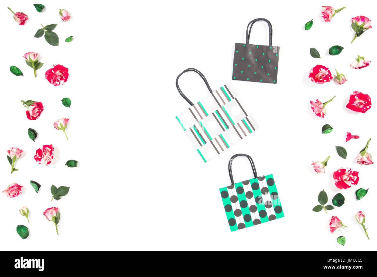 Three paper shopping bags and rose flowers frame on white background ...