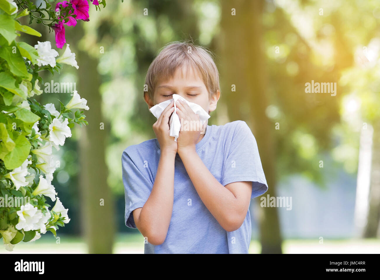 Allergy. Kid is blowing his nose near blossoming flowers Stock Photo ...
