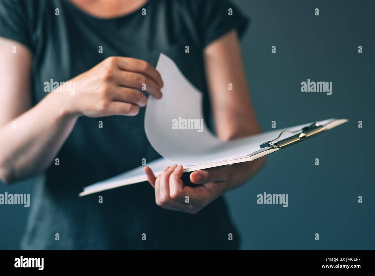 Casual adult female reading notes from notepad paper, unrecognizable ...