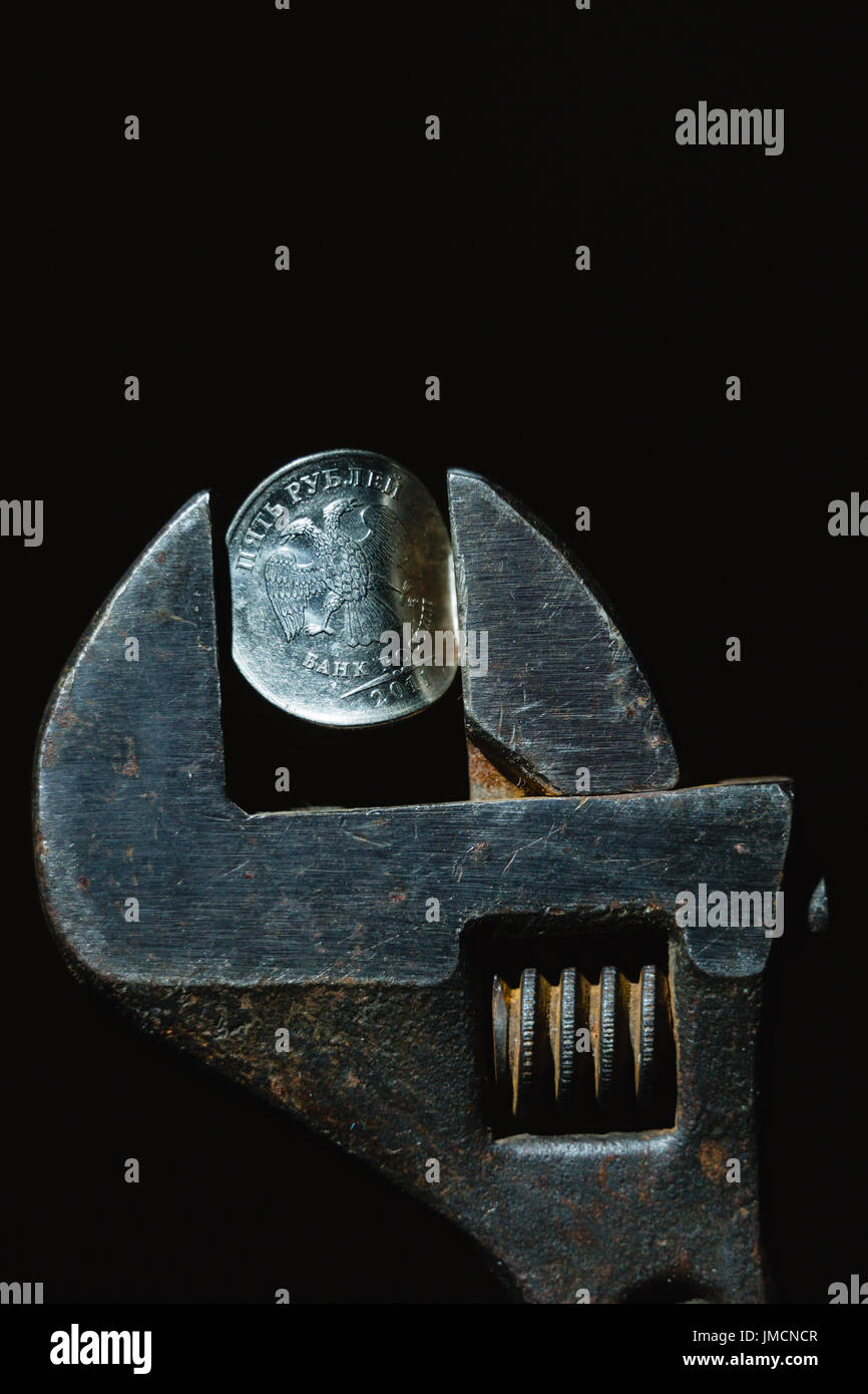 The coin in vise on the black background as a symbol of economic ... The coin in vise on the black background as a symbol of economic ...