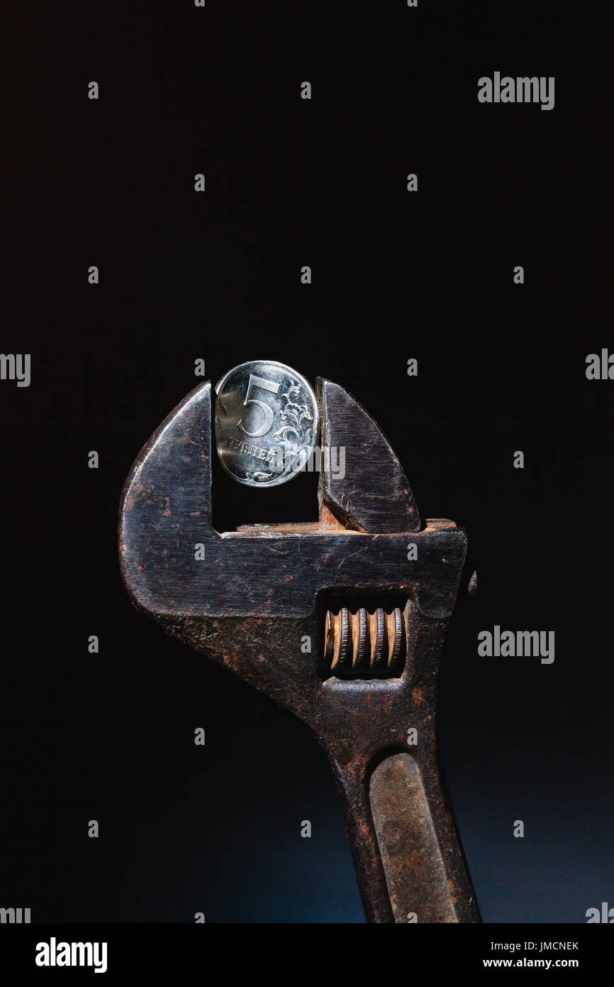 The coin in vise on the black background as a symbol of economic ...
