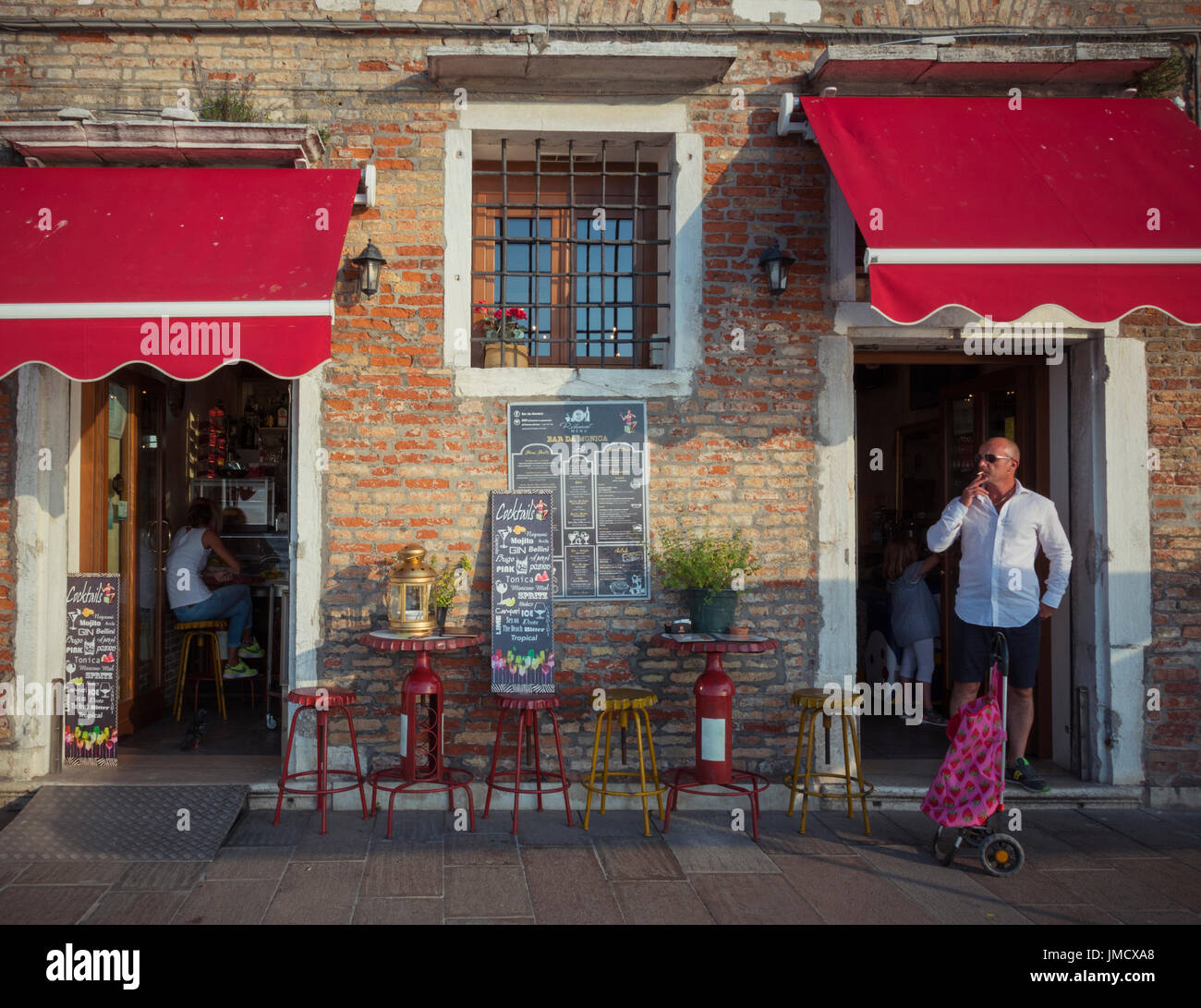 Man smoking a cigarette outside a cafe on Giudecca Island, Venice ...