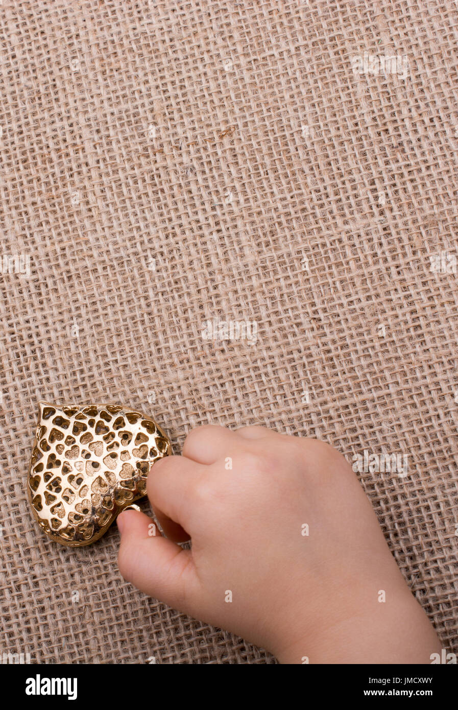 Heart shaped gold color metal object in hand Stock Photo - Alamy