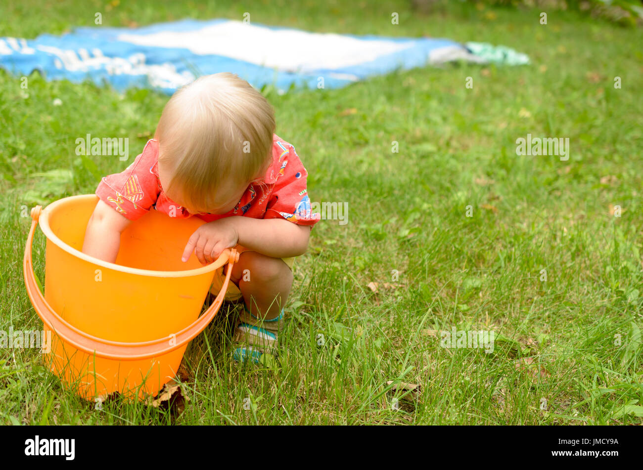 Little girl is playing with an empty bucket Stock Photo - Alamy