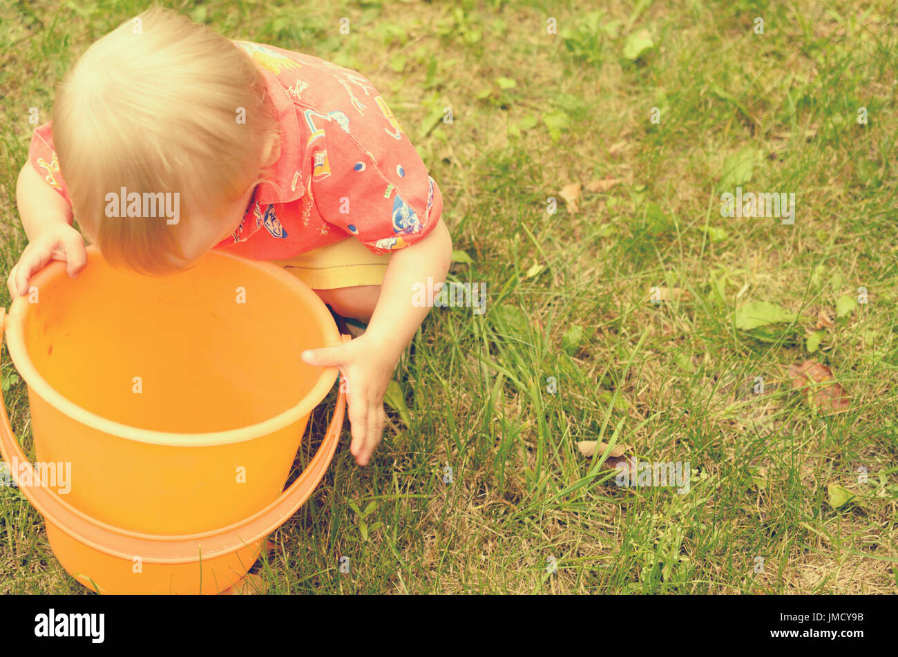 Little girl is playing with an empty bucket Stock Photo - Alamy