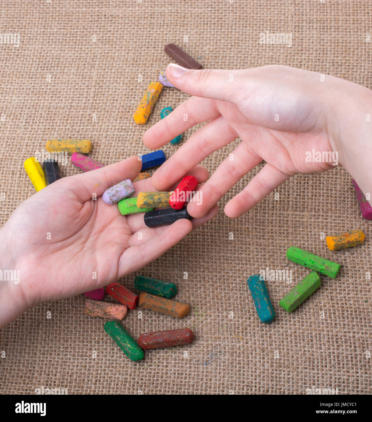 Used color crayons and a hand giving out some Stock Photo - Alamy