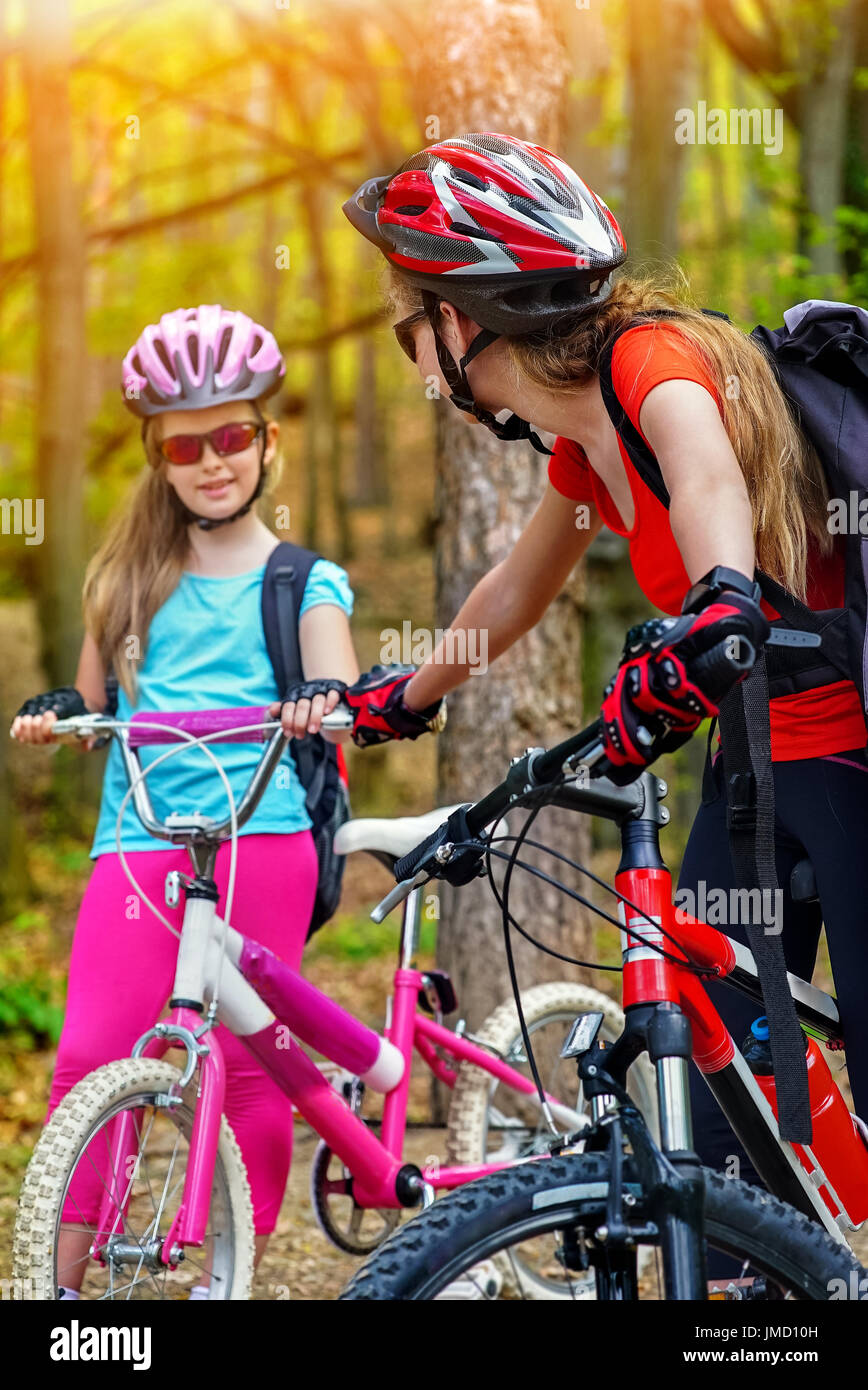 Bikes cycling family. Happy mother and daughter wearing helmet are ...
