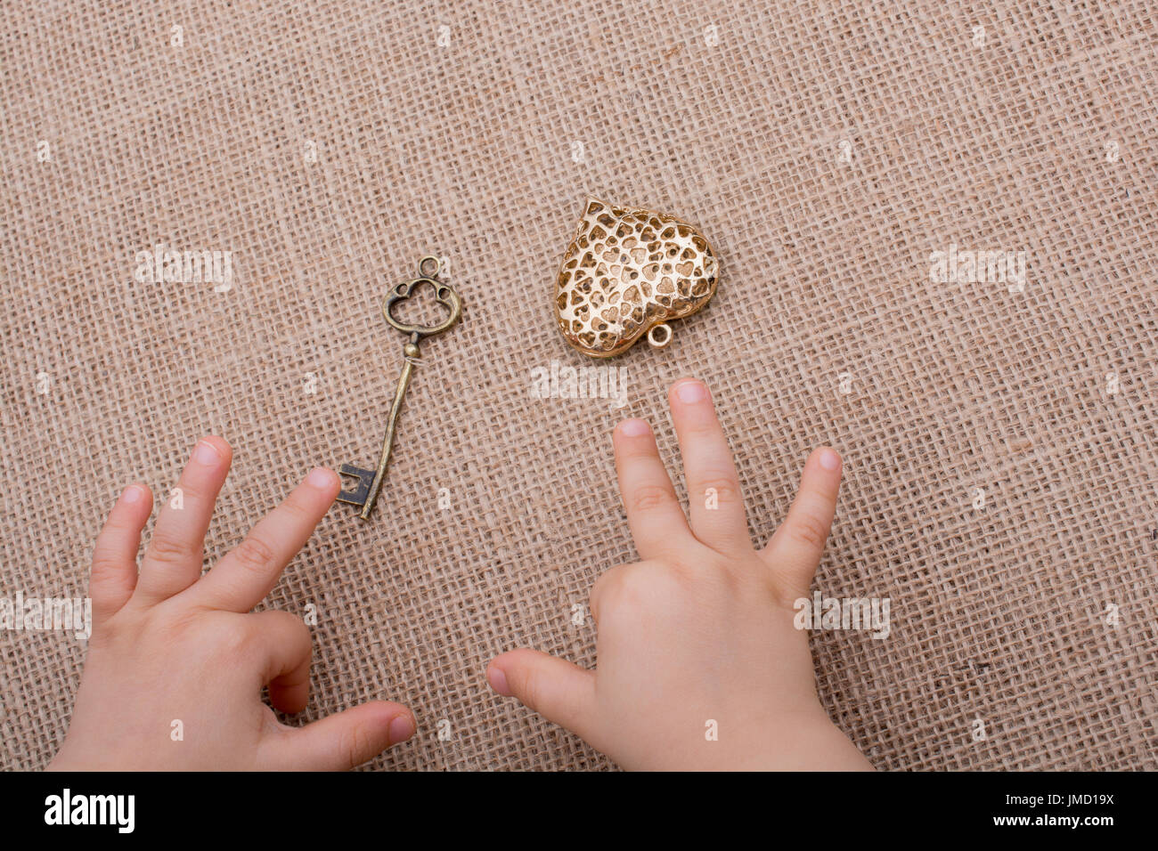 Heart shaped gold color metal object beside a hand Stock Photo - Alamy