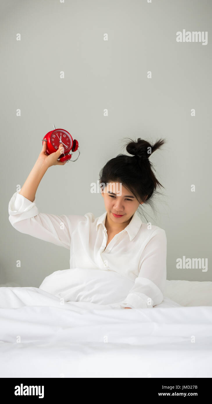 Asian woman woman throwing alarm clock in the morning on the weekend in ...