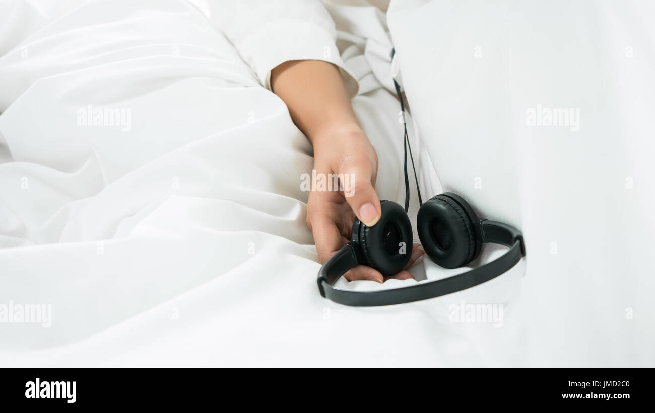 Asian Woman hand with earphone on bed in relex and entertainment ...