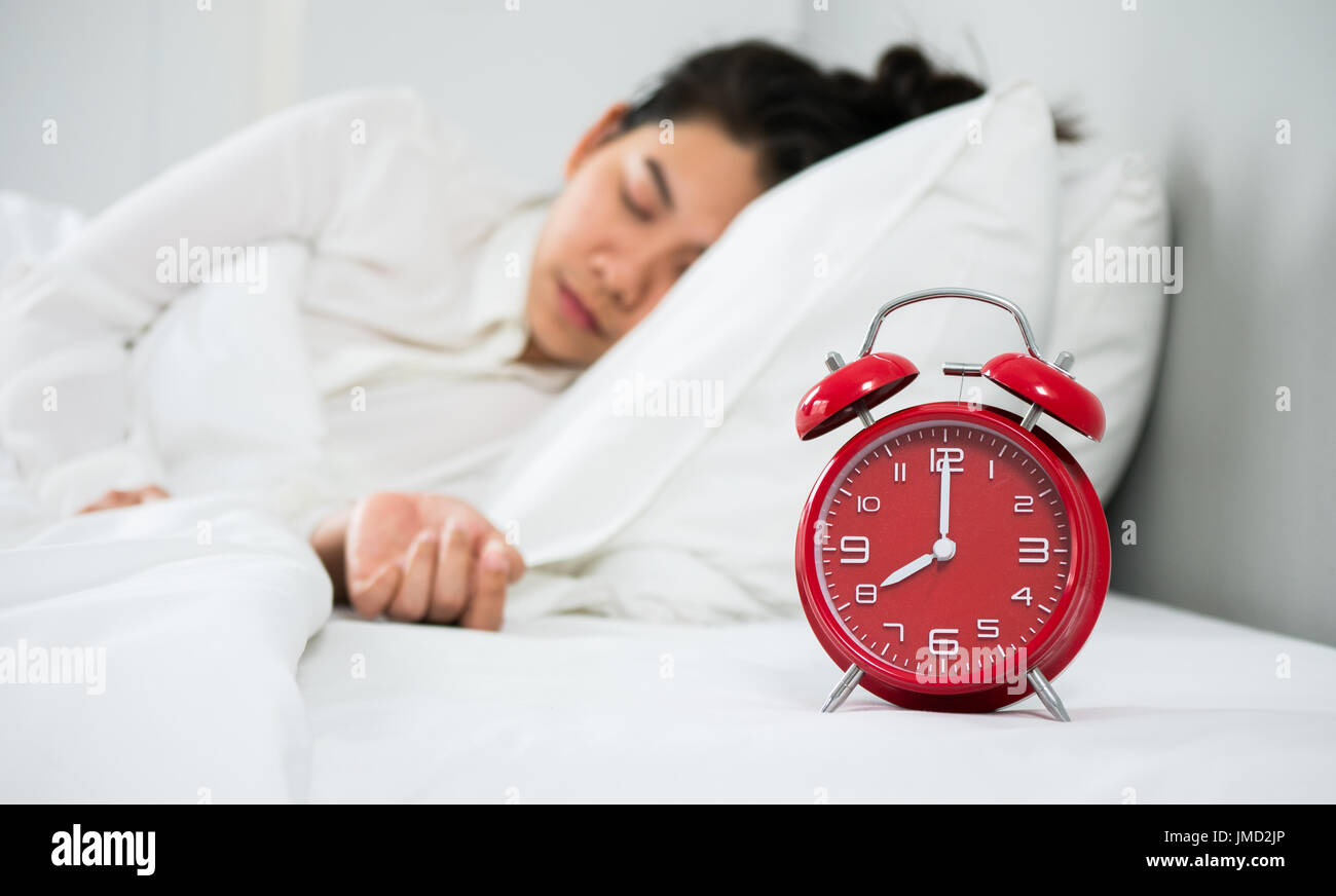 Asian women sleep on the bed with alarm clock in the morning on the ...