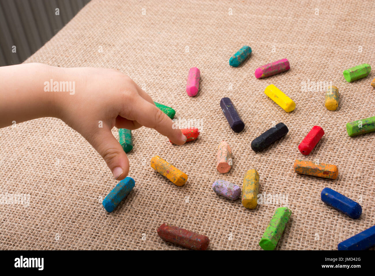Used color crayons and a toddlers hand pointing Stock Photo - Alamy