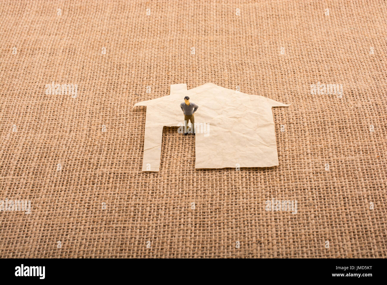 Man figurine and a house shape cut out of paper Stock Photo - Alamy