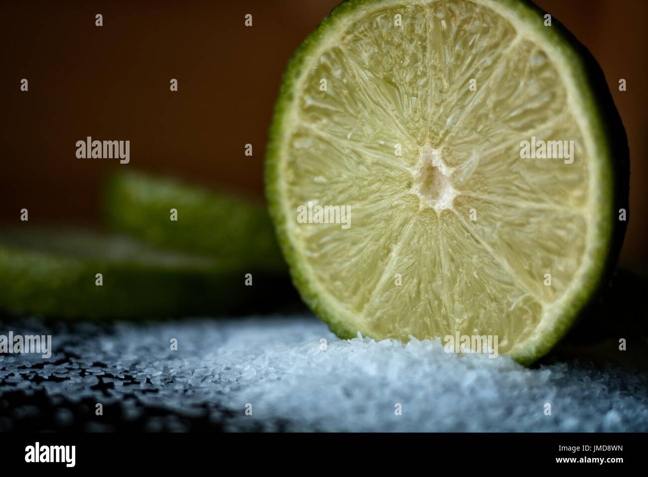 Dramatic photo of a lime slice in kosher salt with lime slices in the ...