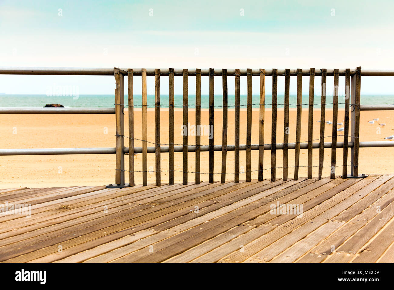Boardwalk, empty beach and ocean. Wooden picket railing. View toward ...