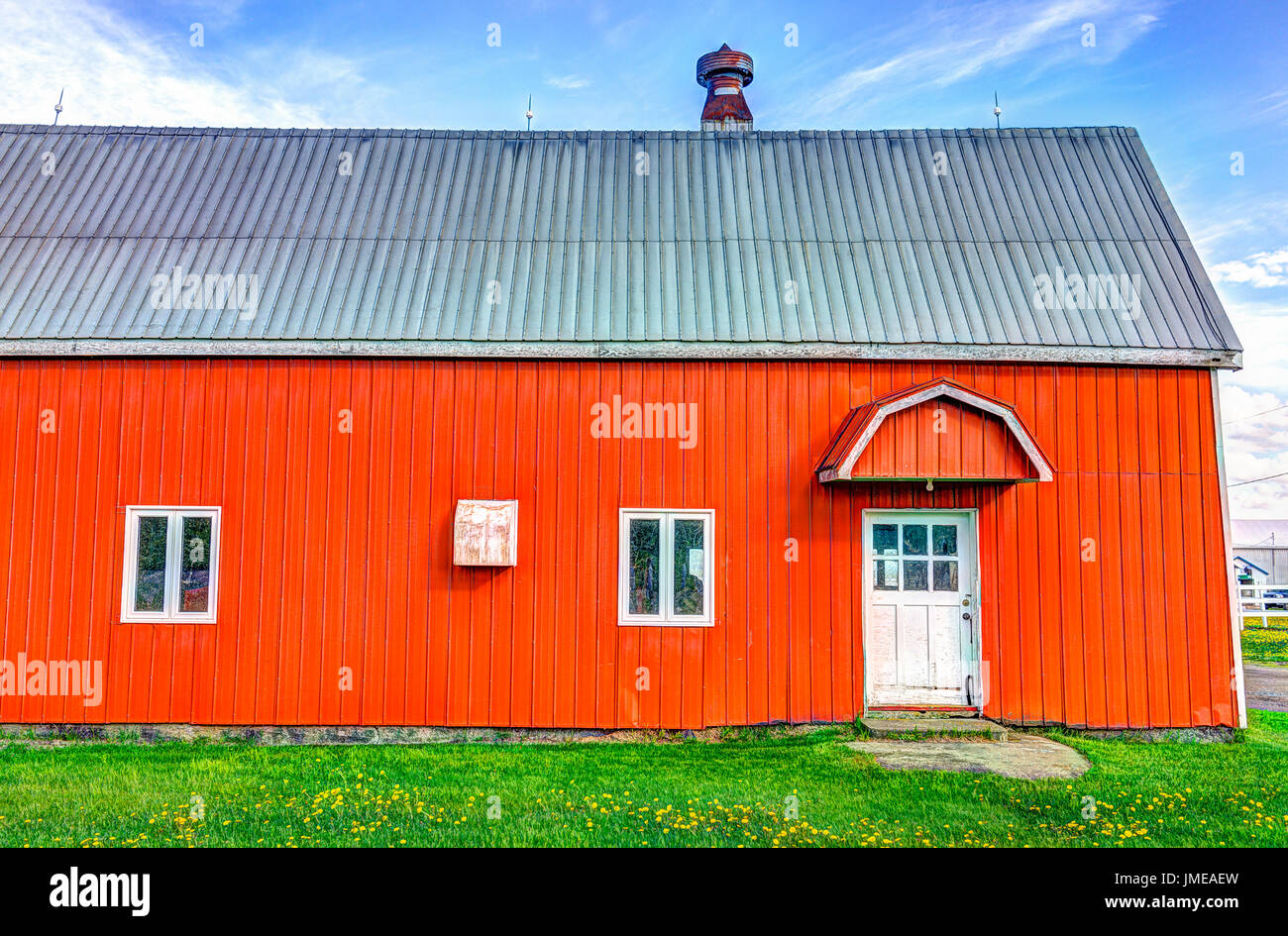 Red orange painted barn shed with white door in summer landscape field ...