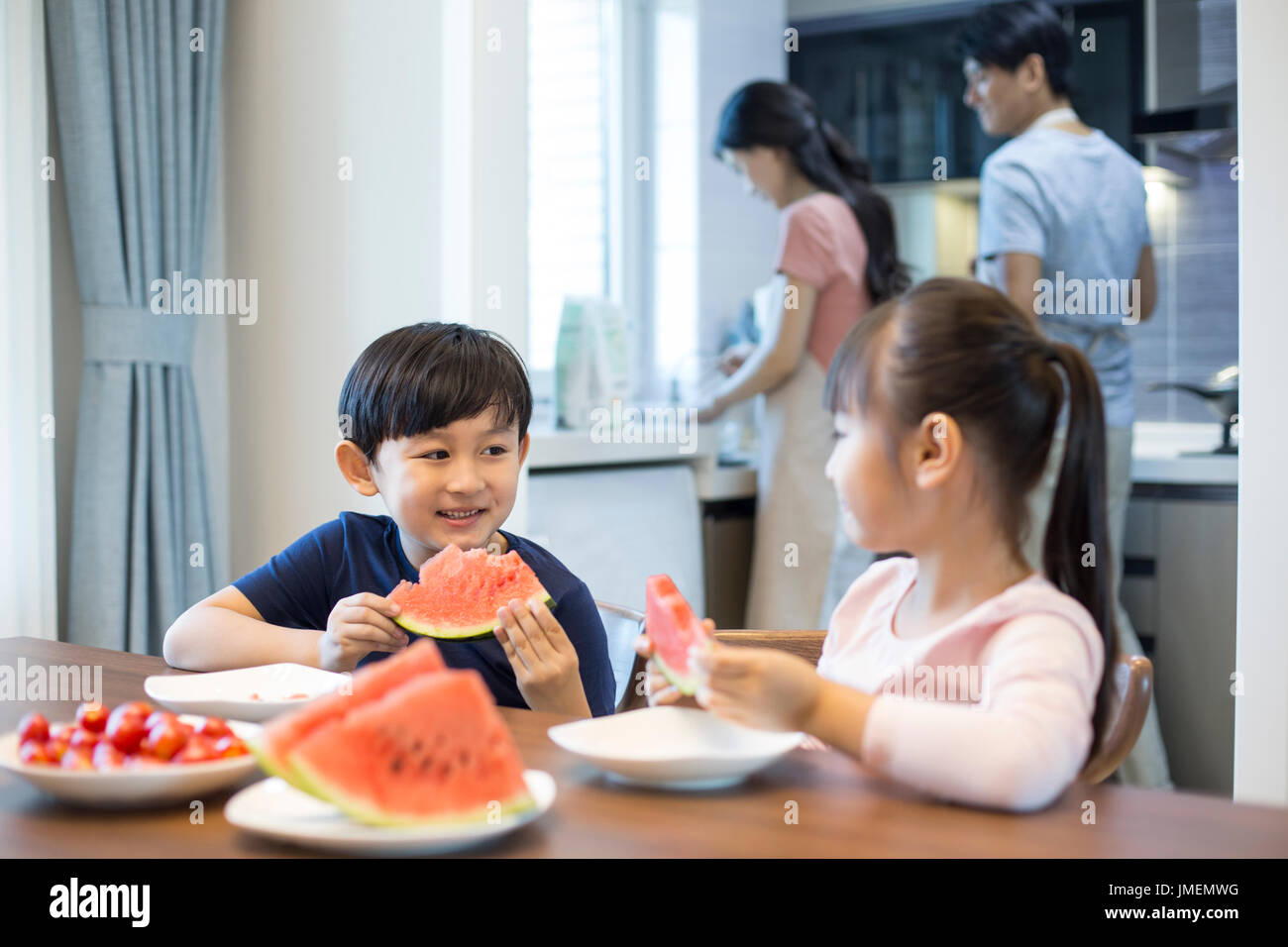 Happy Chinese siblings eating watermelon Stock Photo - Alamy