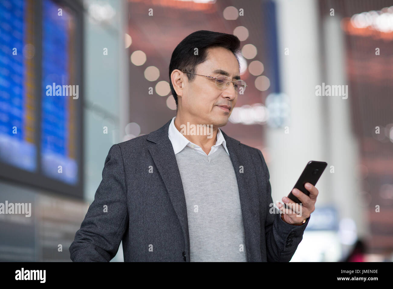 Chinese businessman using smart phone in airport Stock Photo - Alamy