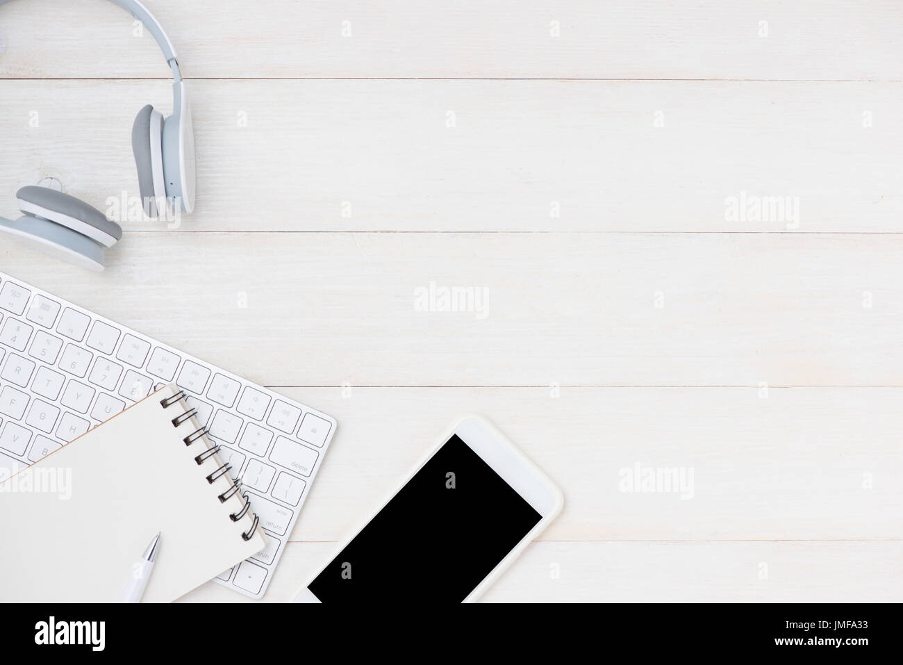 Notepad and computer keyboard on white table with headphone. View from ...