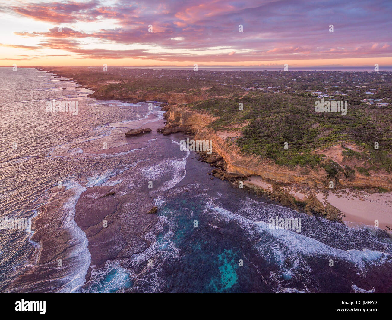 Aerial view of rugged ocean coastline with rural houses in the distance ...
