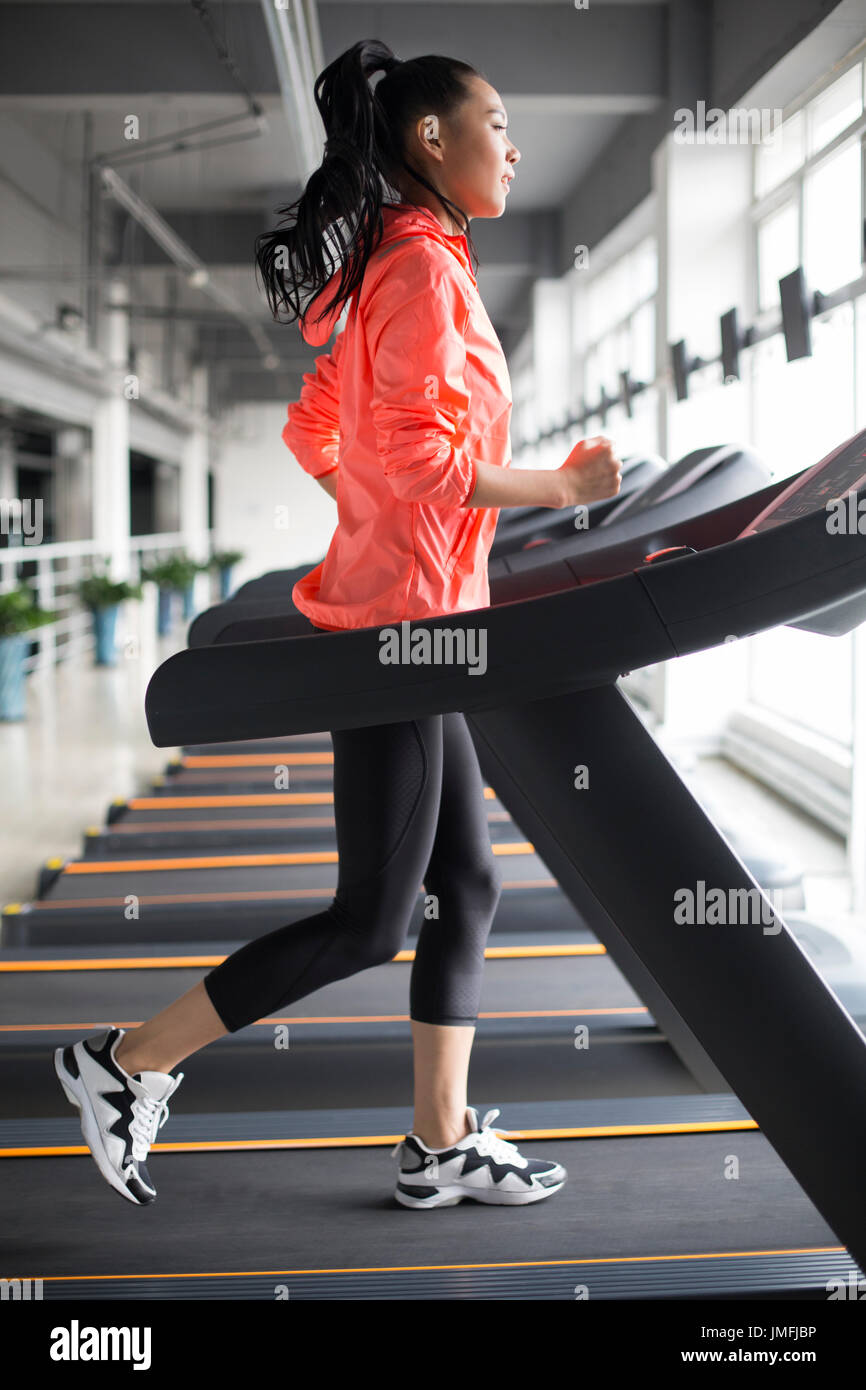 Young Chinese woman running on treadmill in gym Stock Photo - Alamy