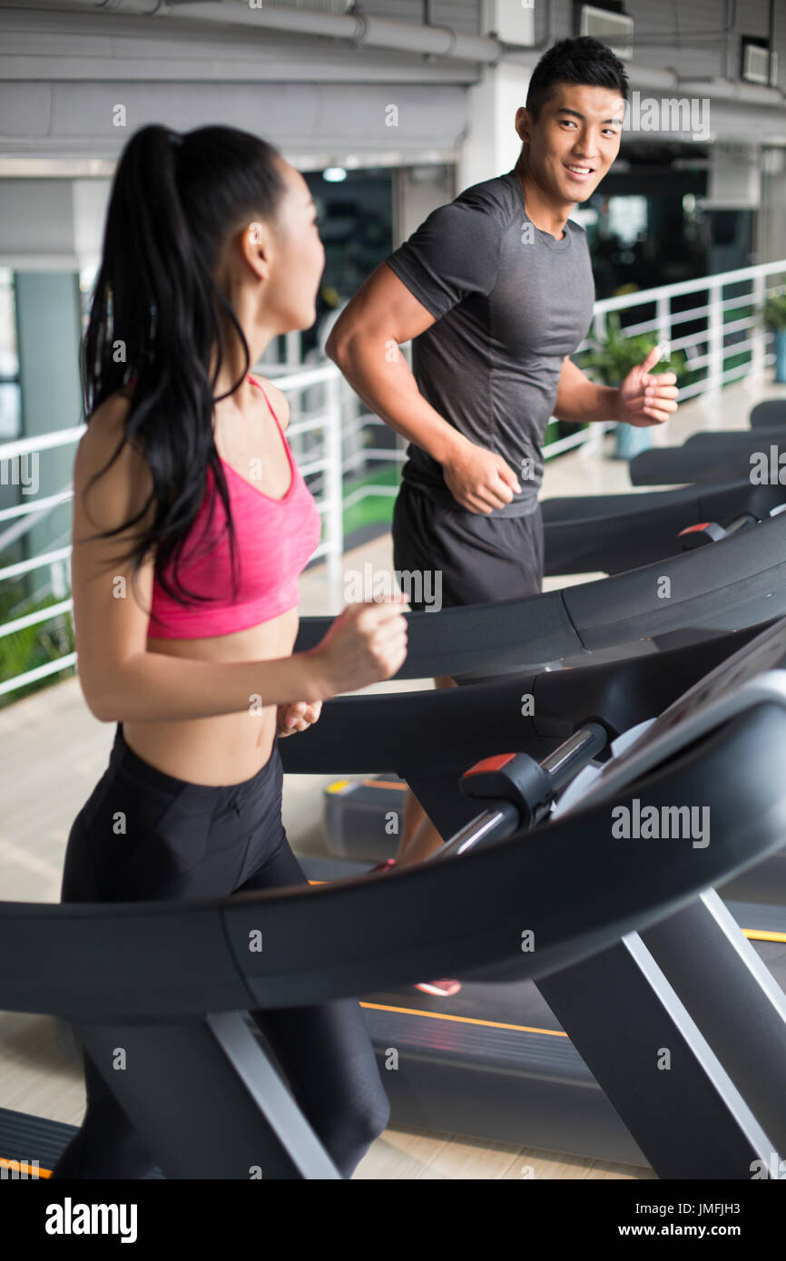 Young Chinese couple running on treadmills in gym Stock Photo - Alamy