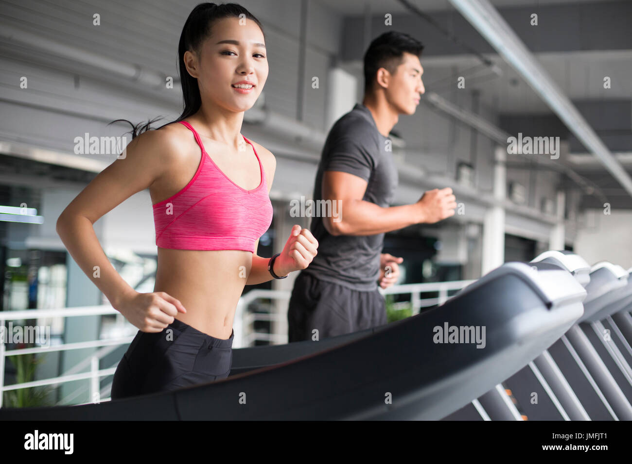 Young Chinese couple running on treadmills in gym Stock Photo - Alamy