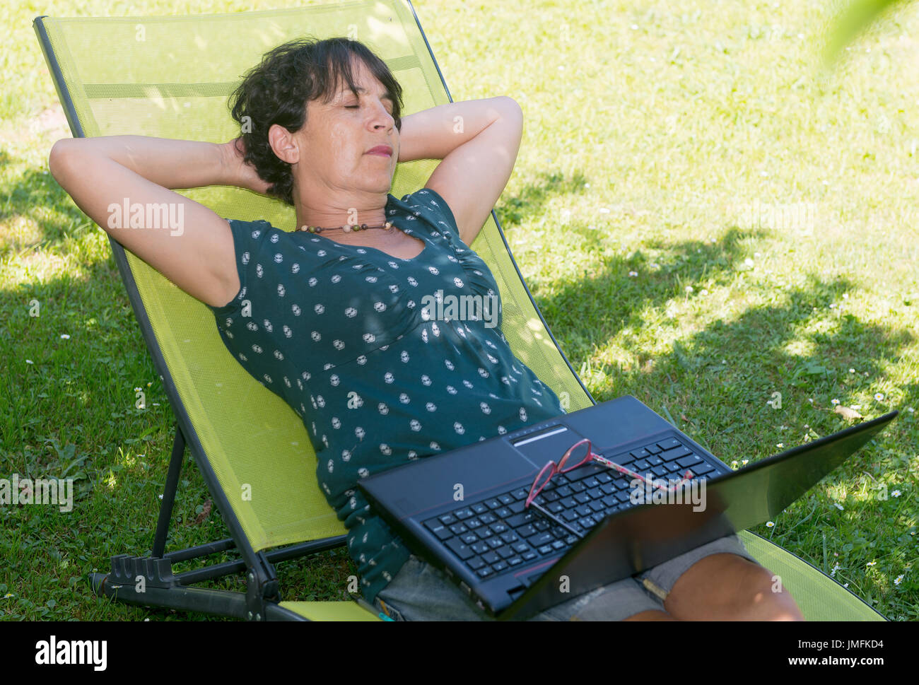 Happy mature woman relaxing resting on the deck chair in the garden ...