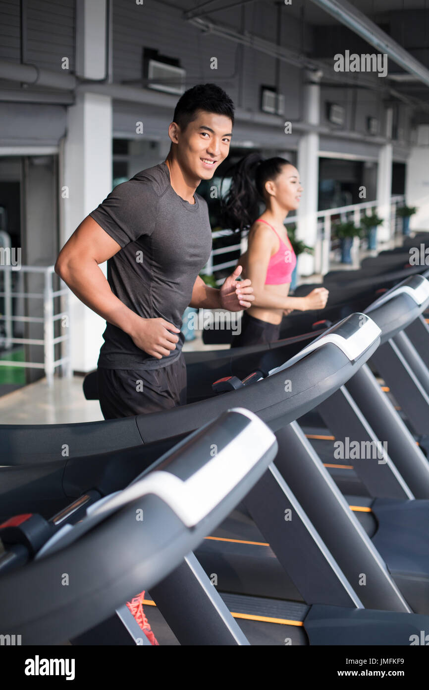 Young Chinese couple running on treadmills in gym Stock Photo - Alamy