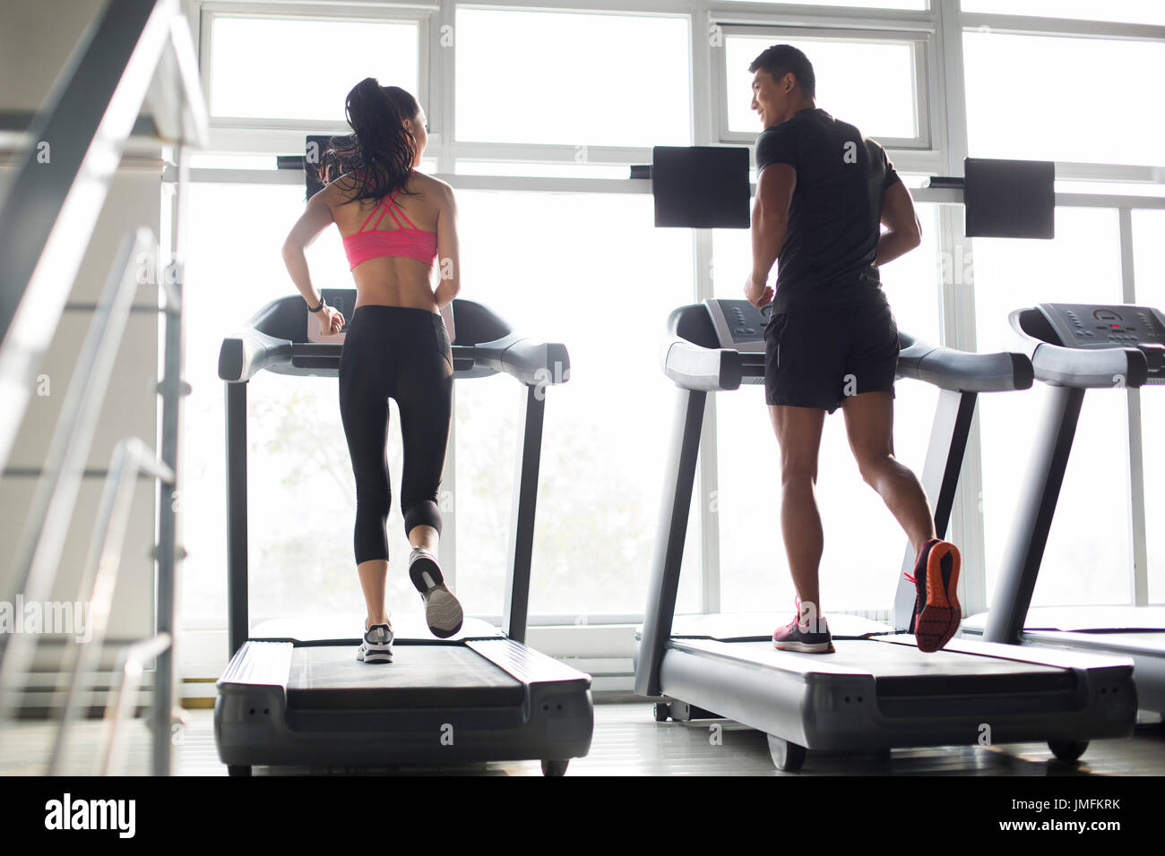 Young Chinese couple exercising on treadmills in gym Stock Photo - Alamy