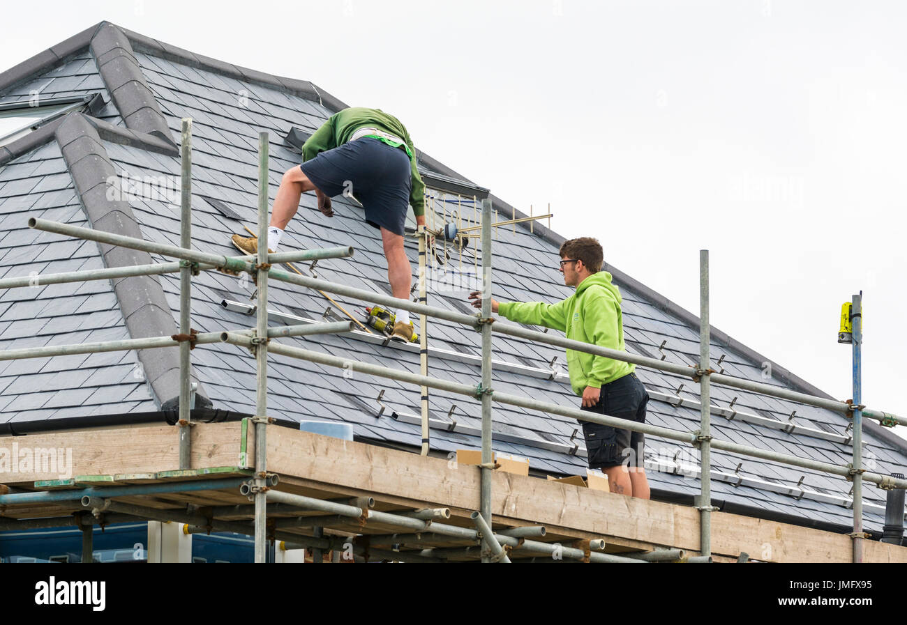 Workmen repairing roof and tiles on the roof of a house Stock Photo - Alamy