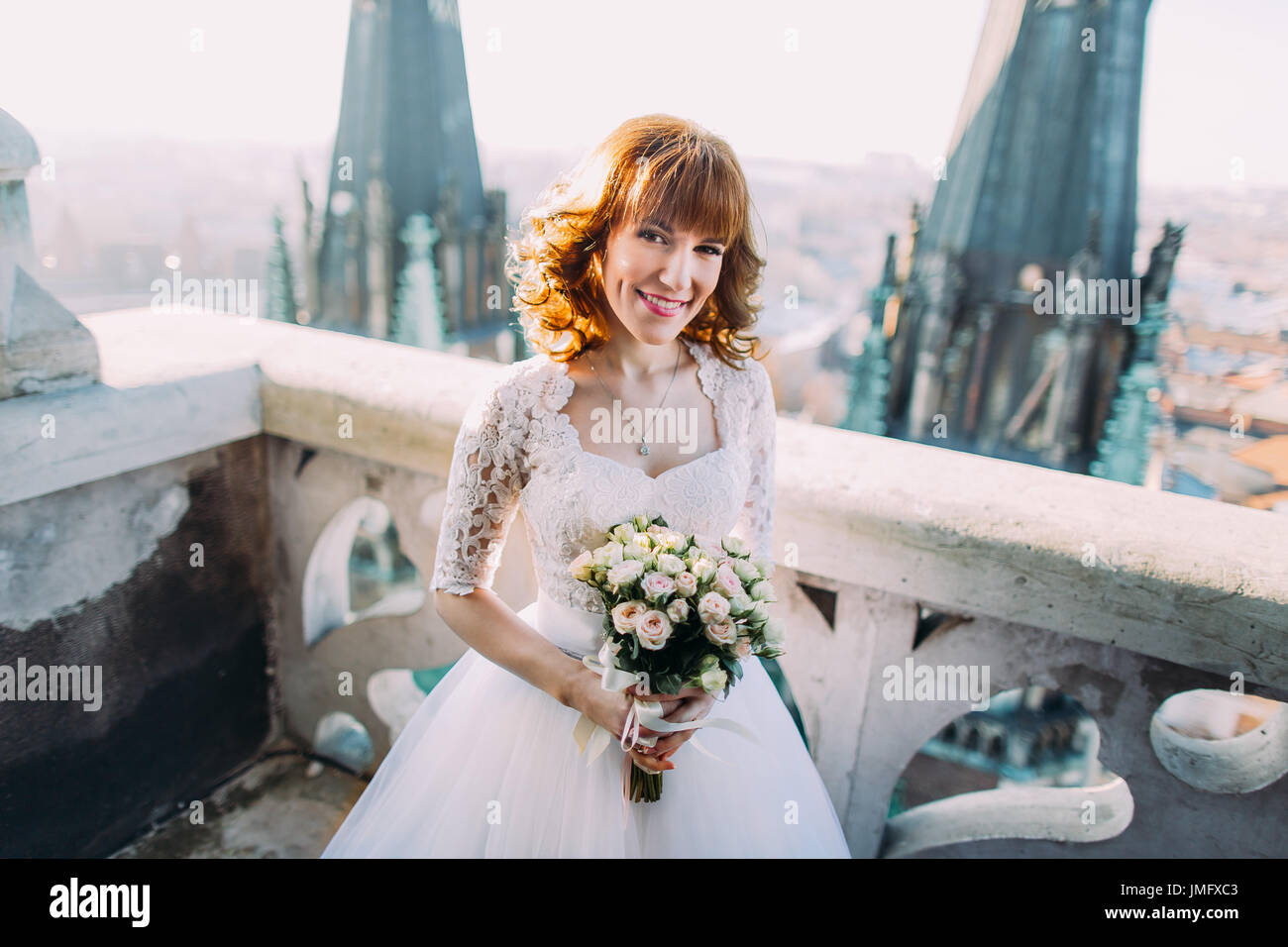 Elegant bride with bridal bouquet poses on the tower balcony of old ...