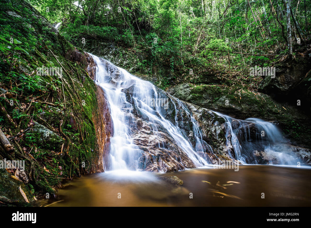Slope waterfall with smooth pouring water inside green tropical ...