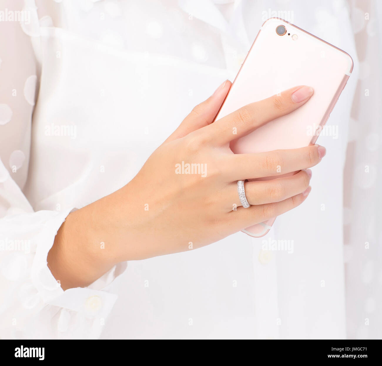 woman’s hand with diamond ring holding cellphone showing the backside ...