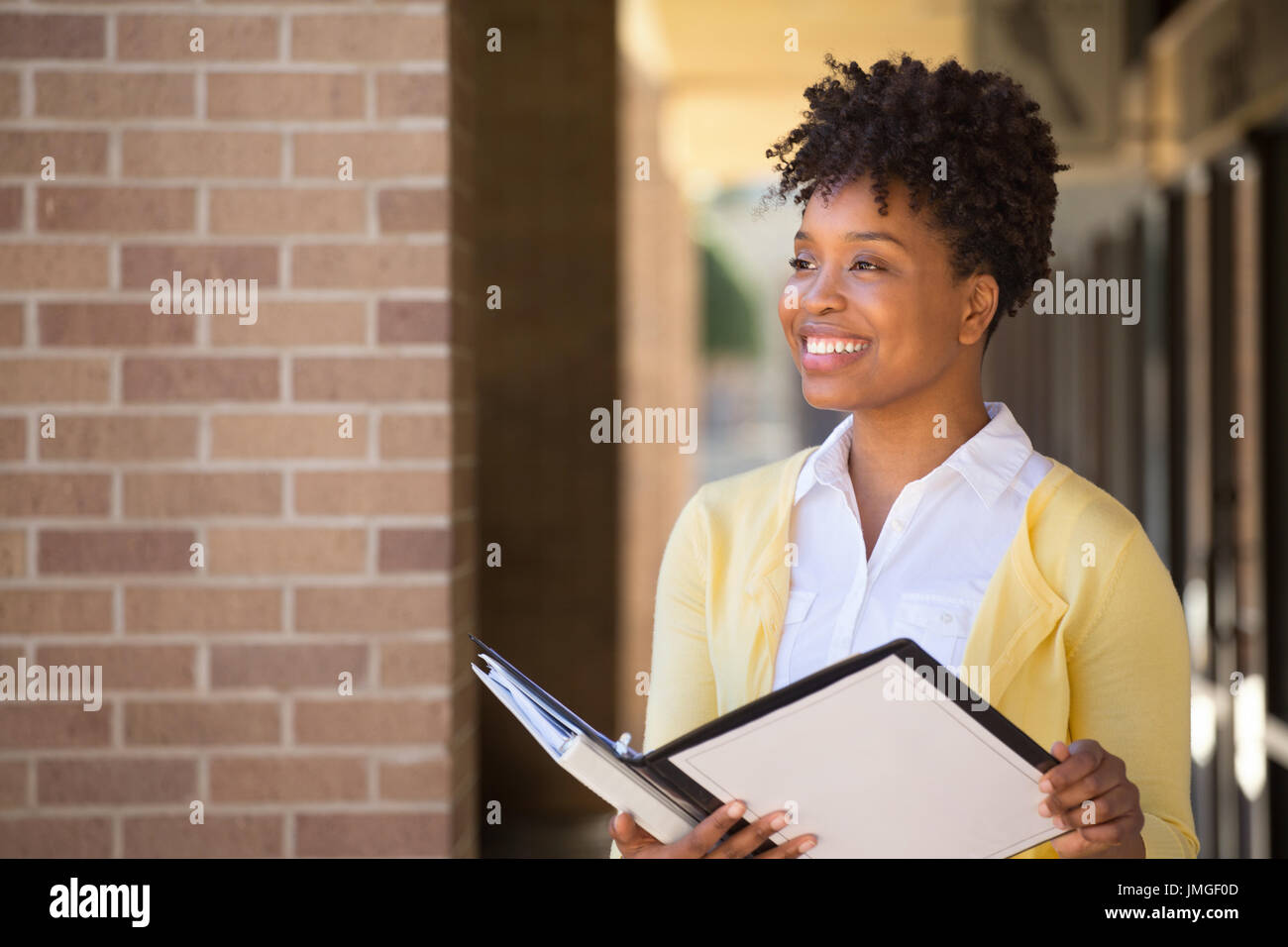 Woman smiling holding a notebook Stock Photo - Alamy
