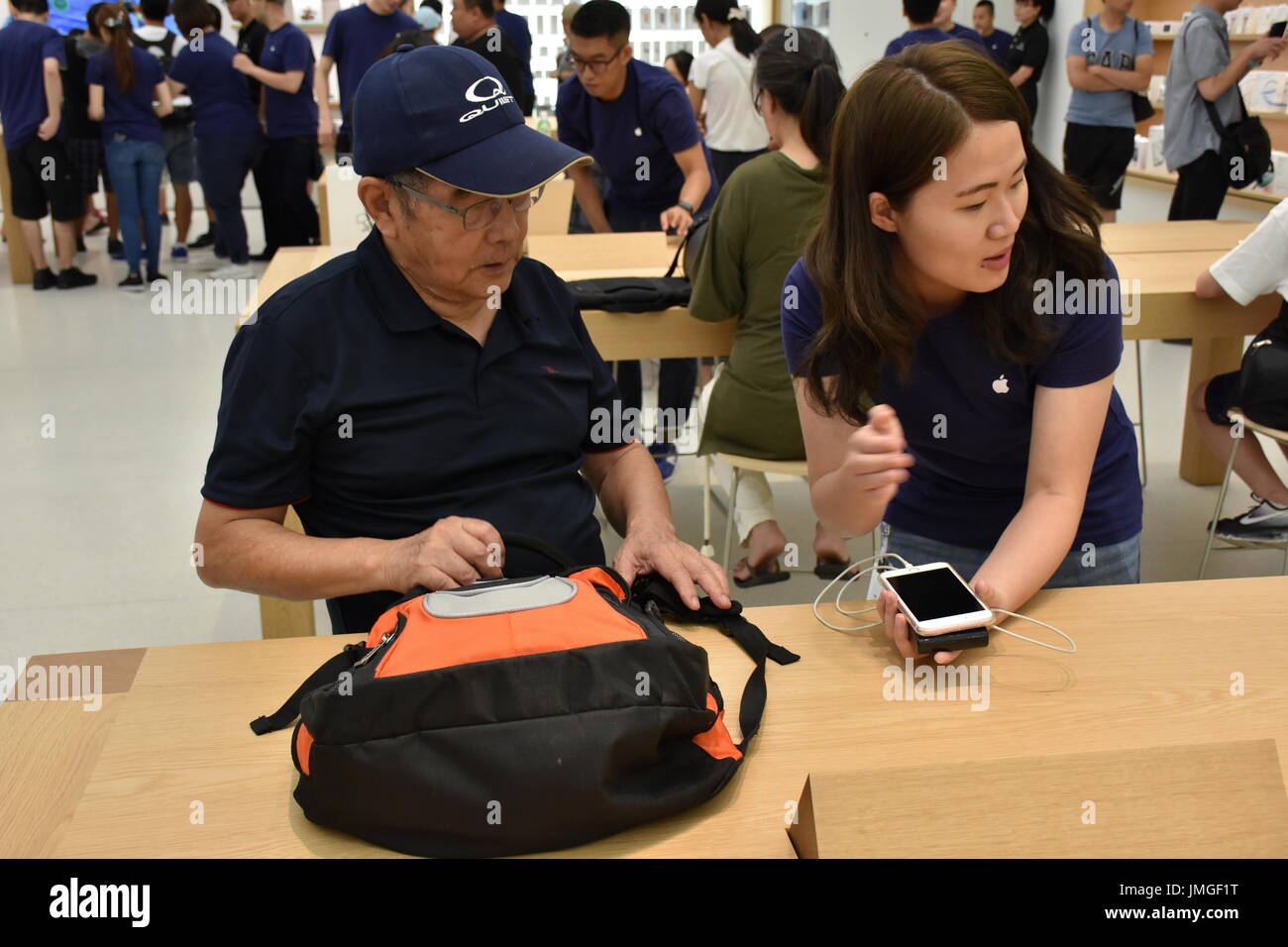 Worker teaches old gentleman to use iPhone at the grand opening of the ...