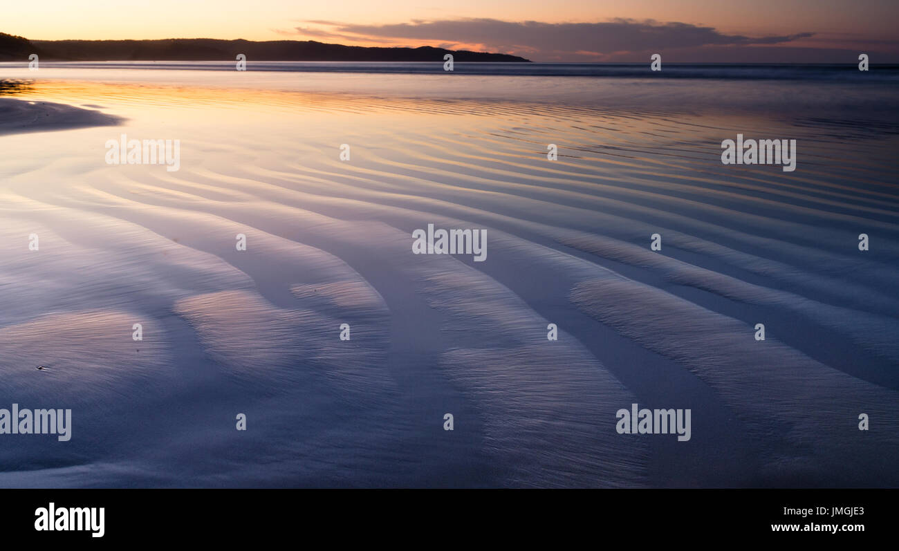 Sunrise over the sand at Cave Beach in Booderee National Park, NSW ...