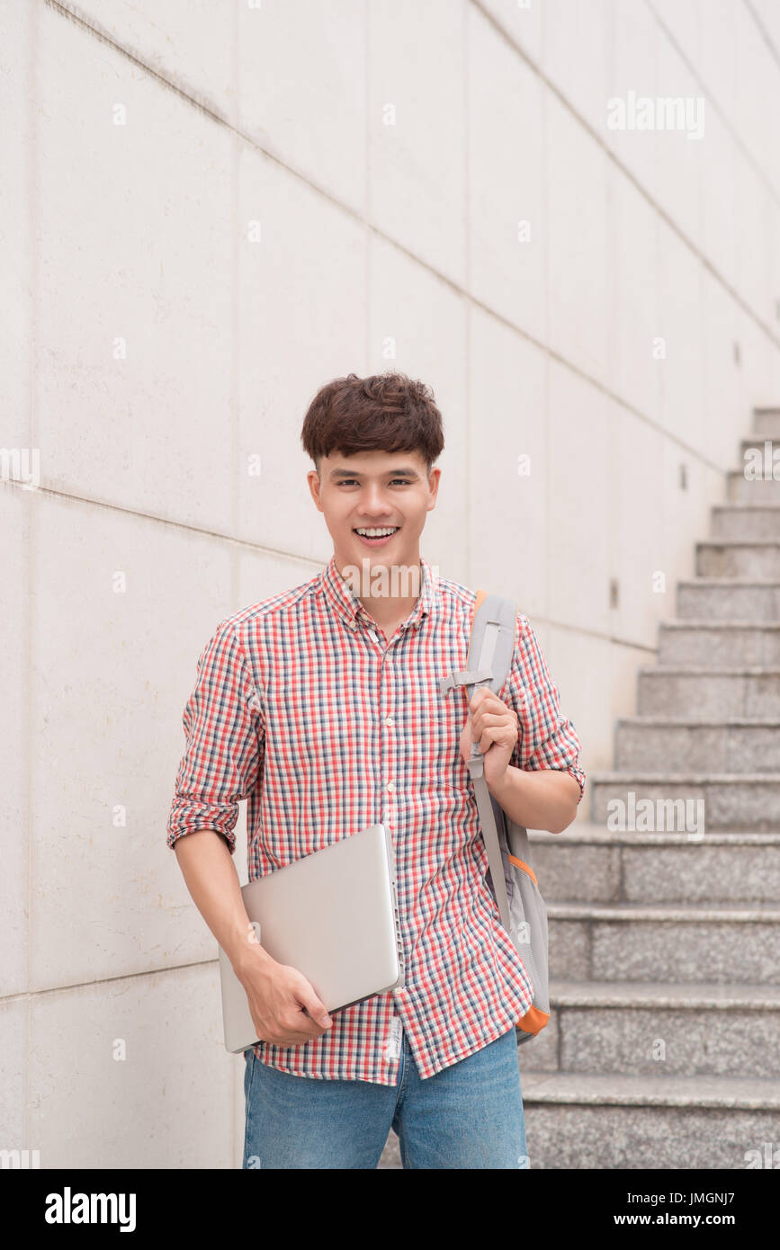 Student holding with laptop computer inside school campus building ...