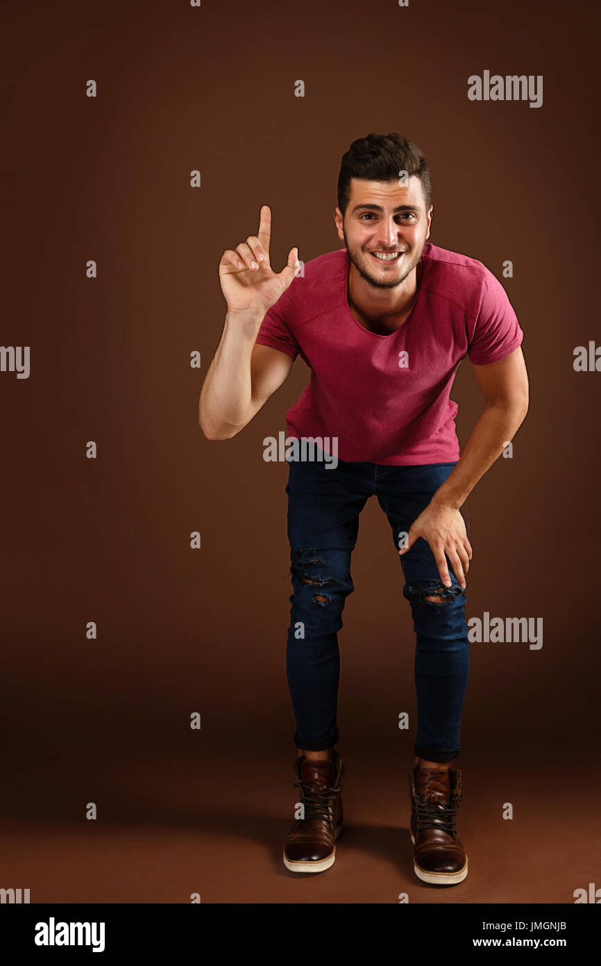 Smiling guy pointing up and looking at camera Stock Photo - Alamy
