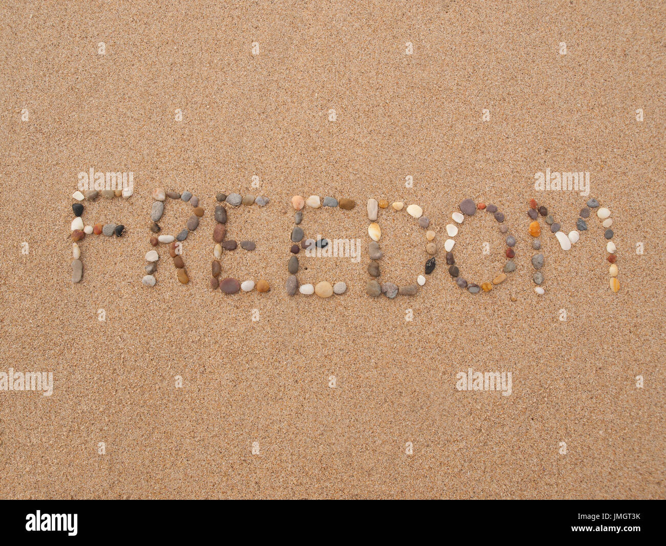 word freedom written with stones and shells on the beach by the ocean ...