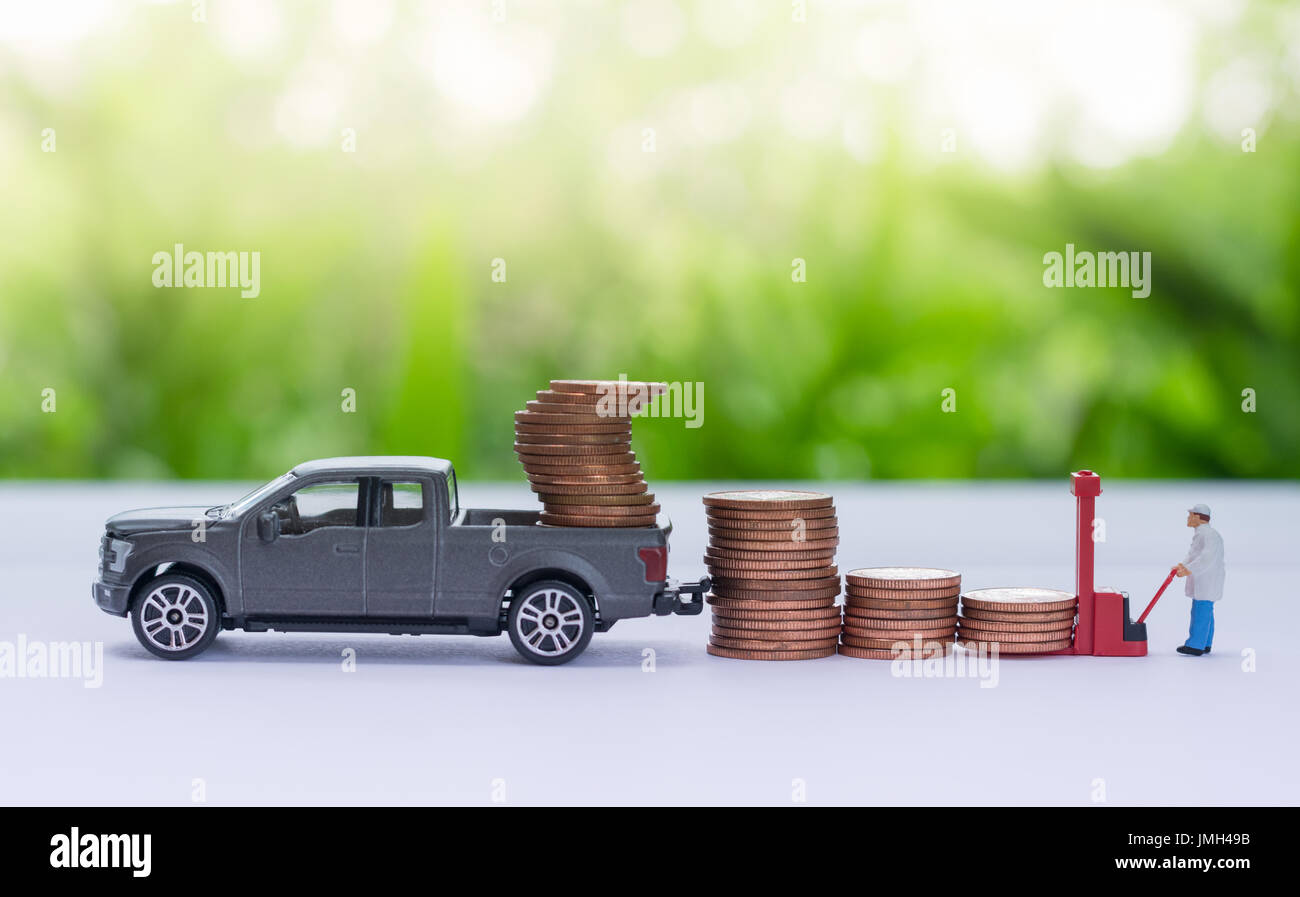 Miniature truck carrying stack of coins, worker loading stack of coins ...