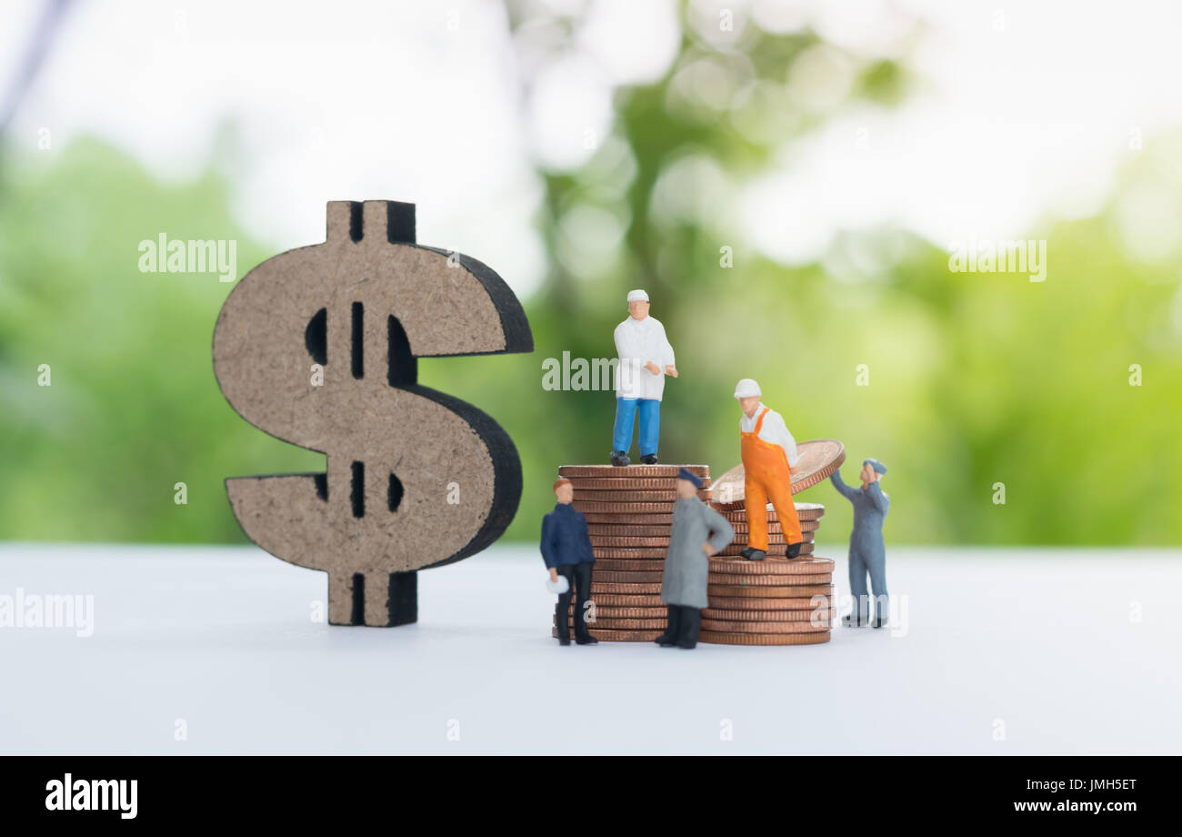 Miniature businessman and worker working together for an income beside ...