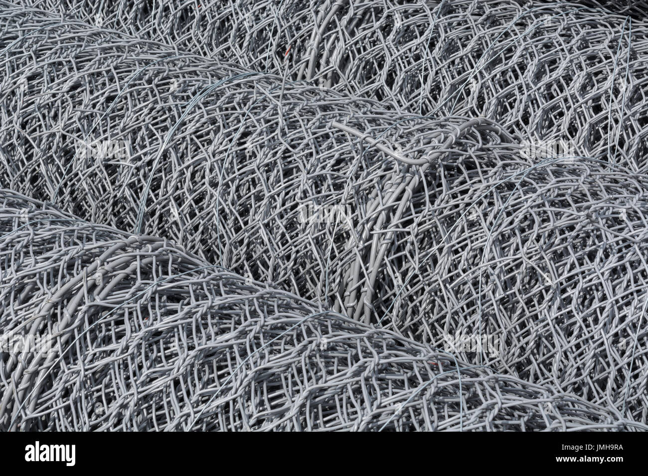 Toughened wire mesh used for retaining cliff face rockfalls and in the ...