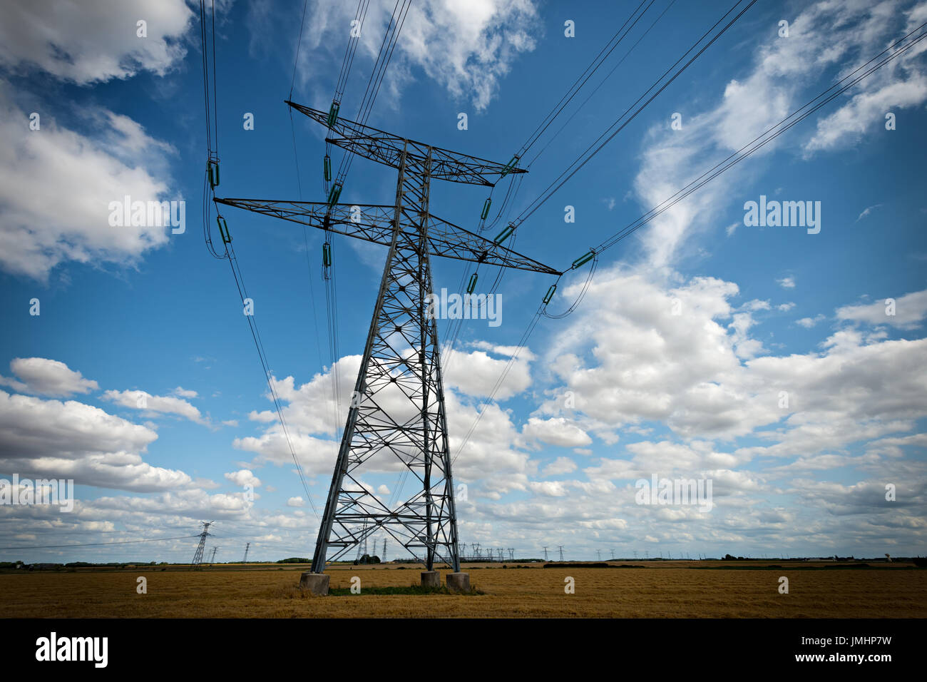 high voltage pylons on blue cloudy sky background Stock Photo - Alamy