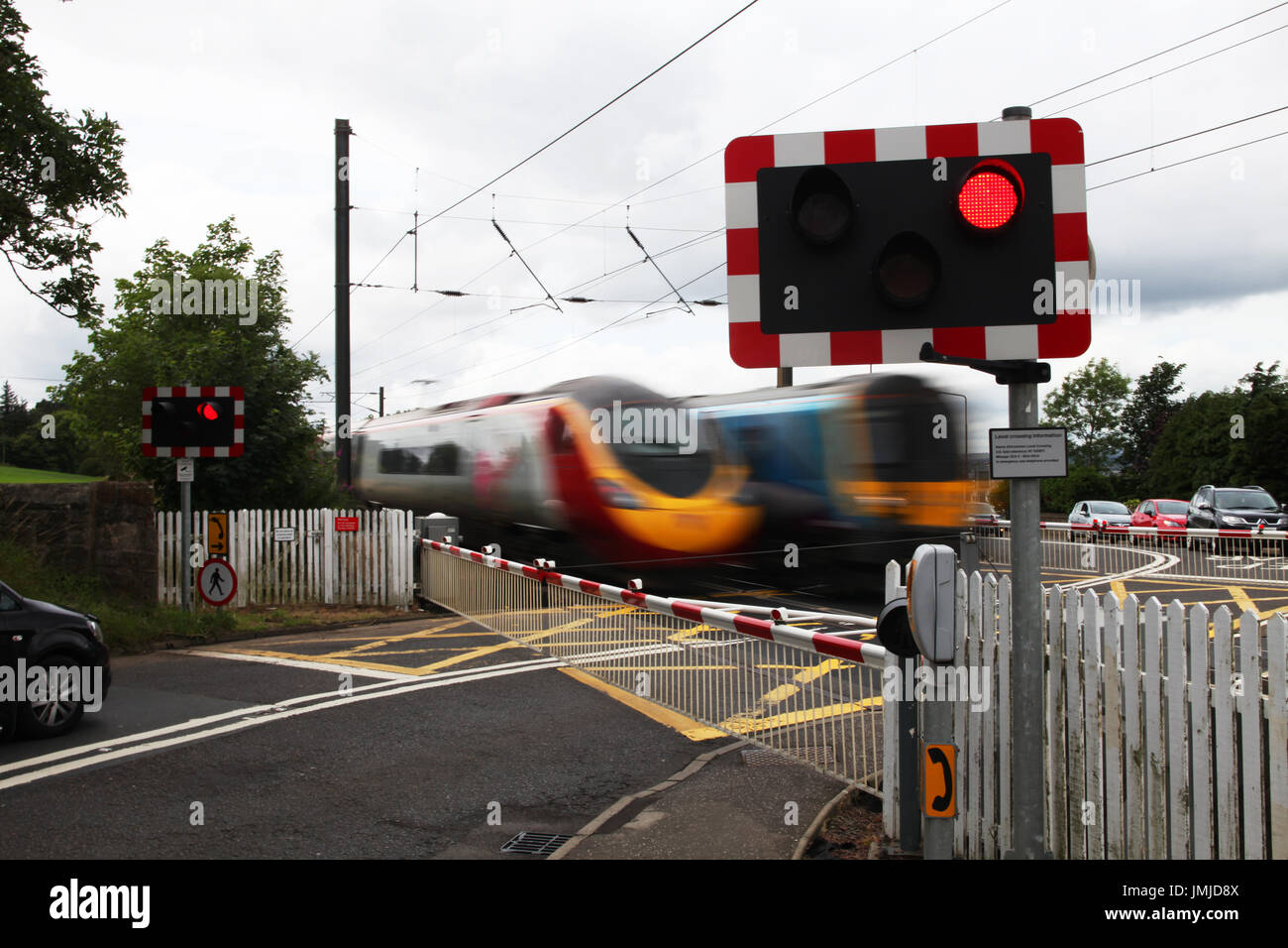 Two trains pass through the level crossing at Kirknewton station whilst ...