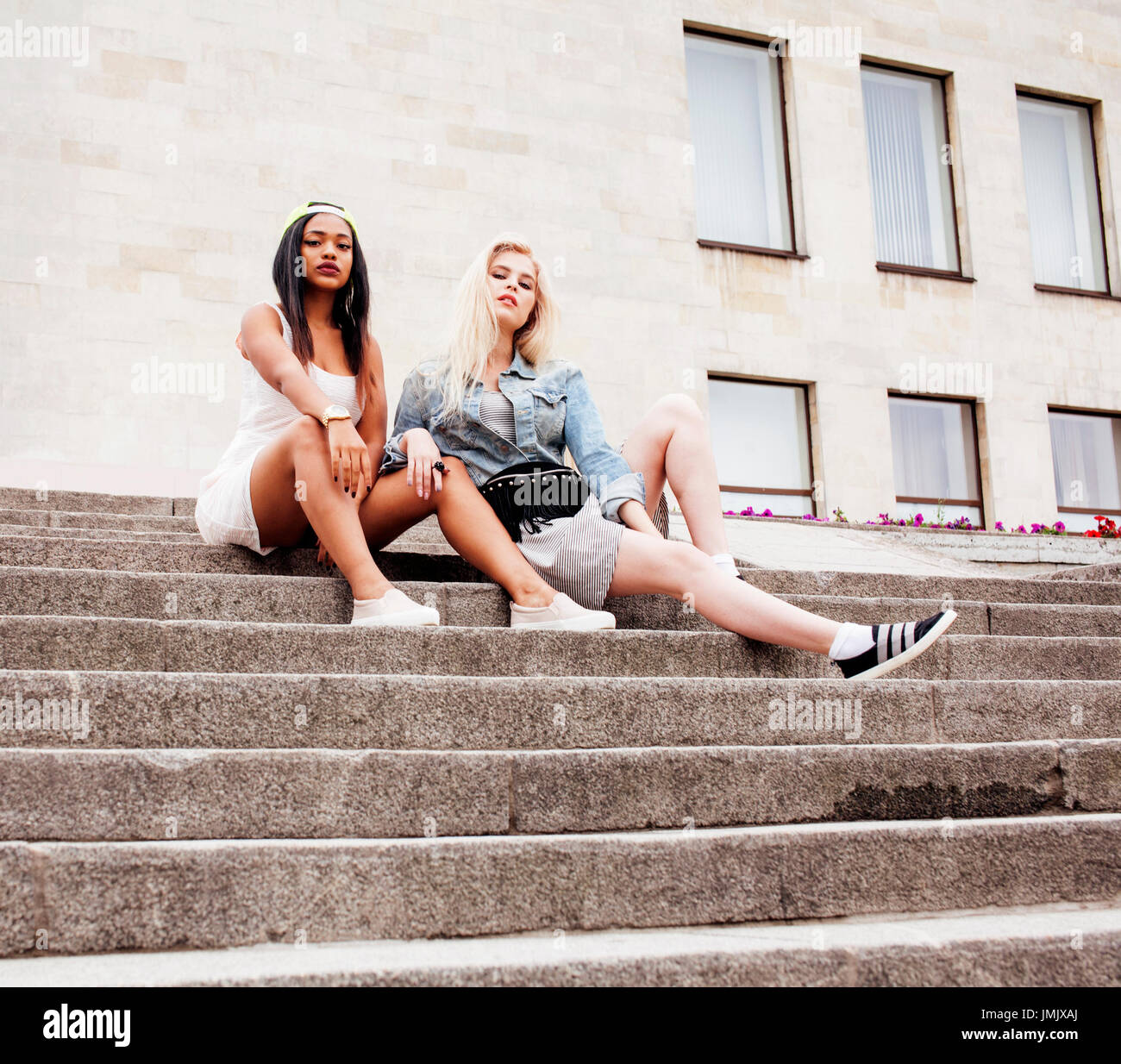 Two teenage girls infront of university building smiling, having fun ...